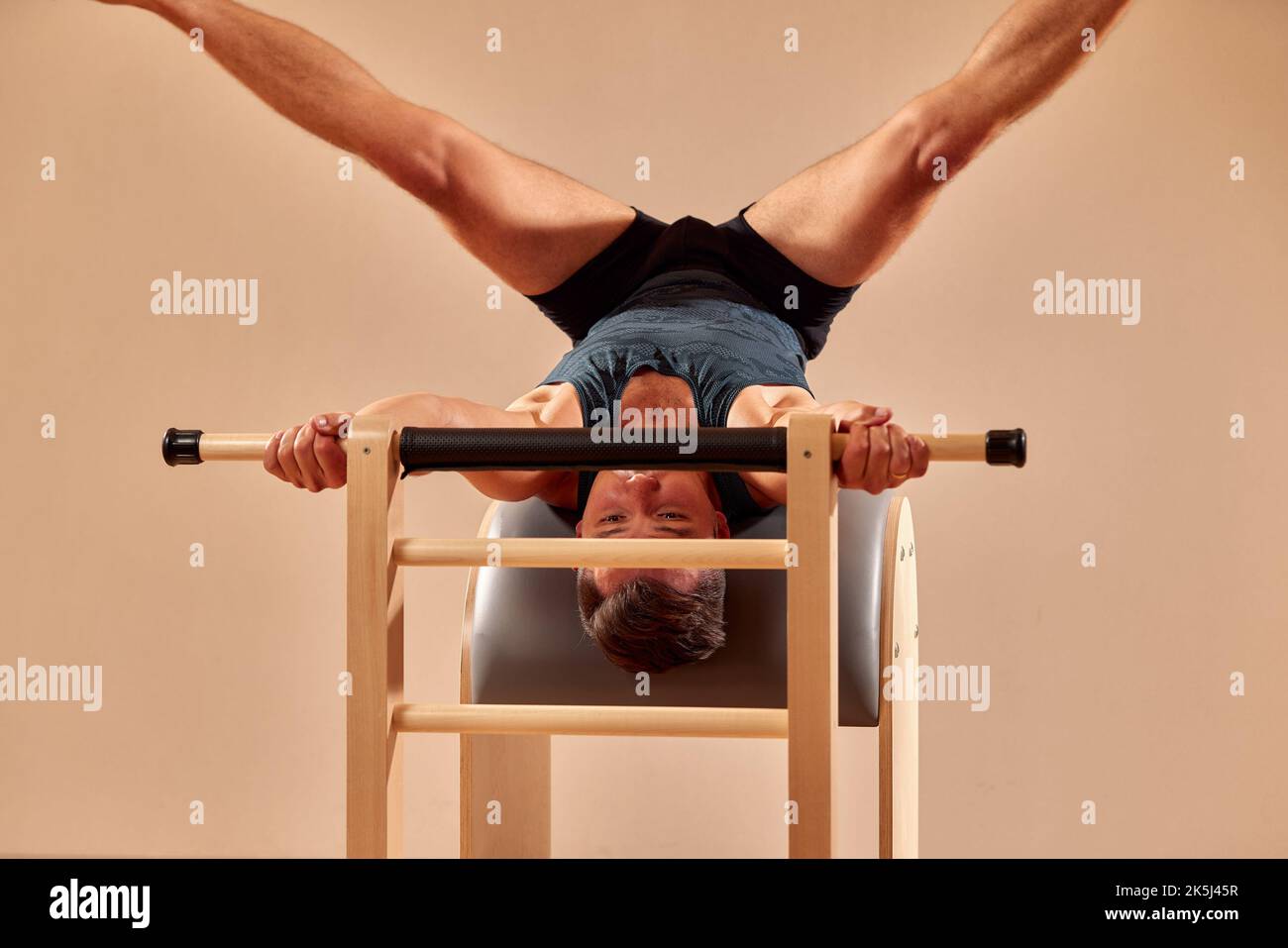 Handsome pilates male instructor performing stretching balance fitness ...
