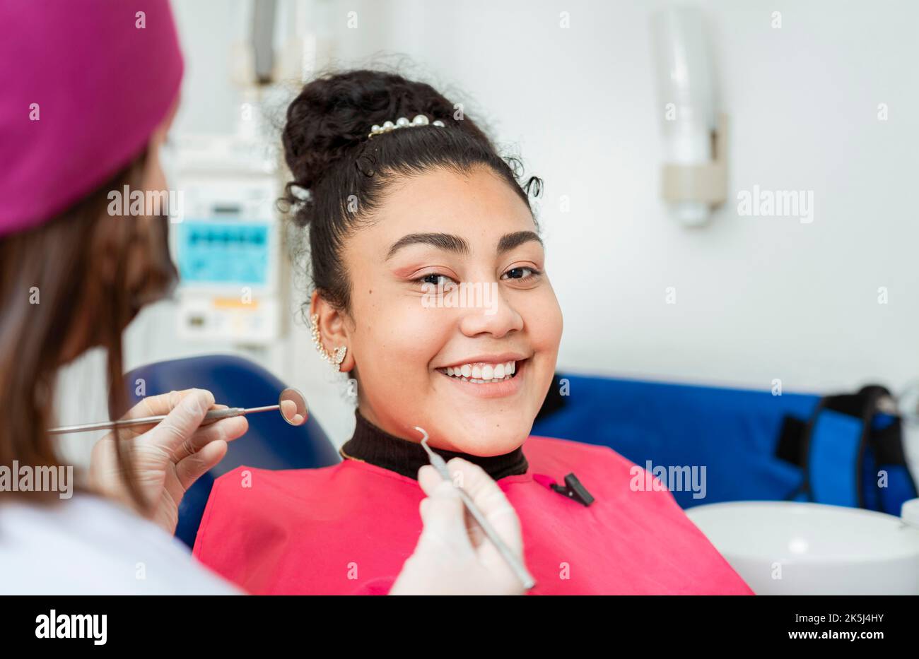 Smiling patient in dentist's chair, Professional dentist examining ...