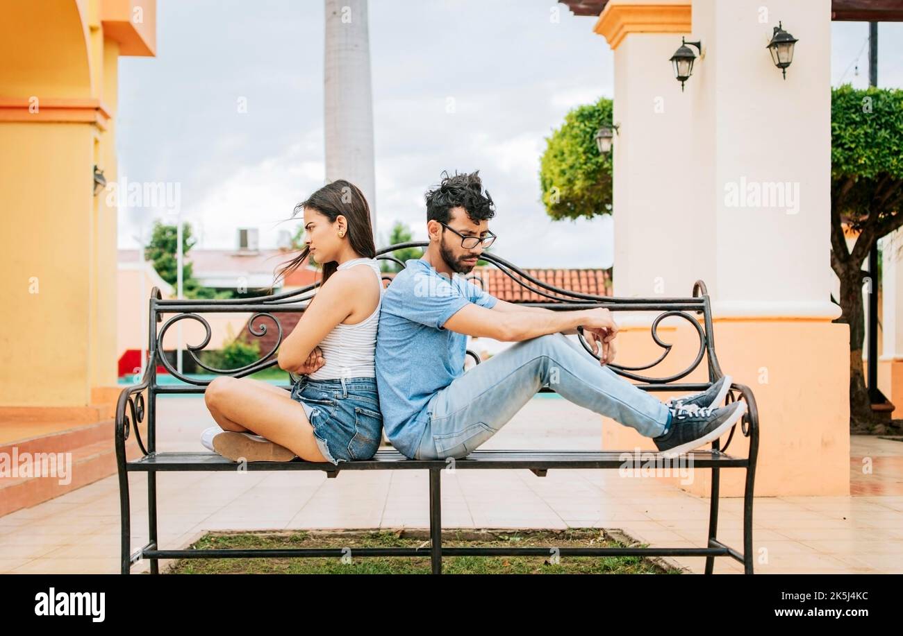 Upset couple sitting back to back on a park bench. Concept of a couple ...