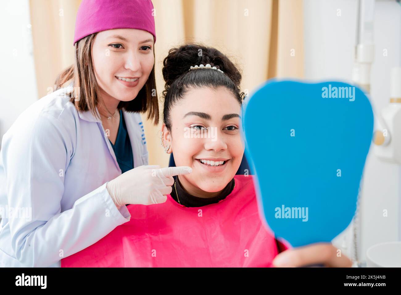 Dentist with satisfied patient smiling at dental mirror, Satisfied patient in dental clinic ...