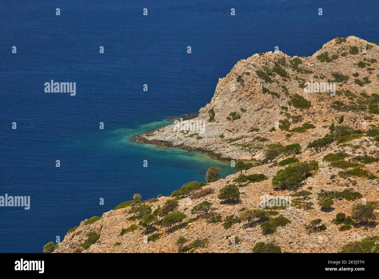 Agios Pavlos beach, pebble beach, barren rocks, trees, blue sea, green ...