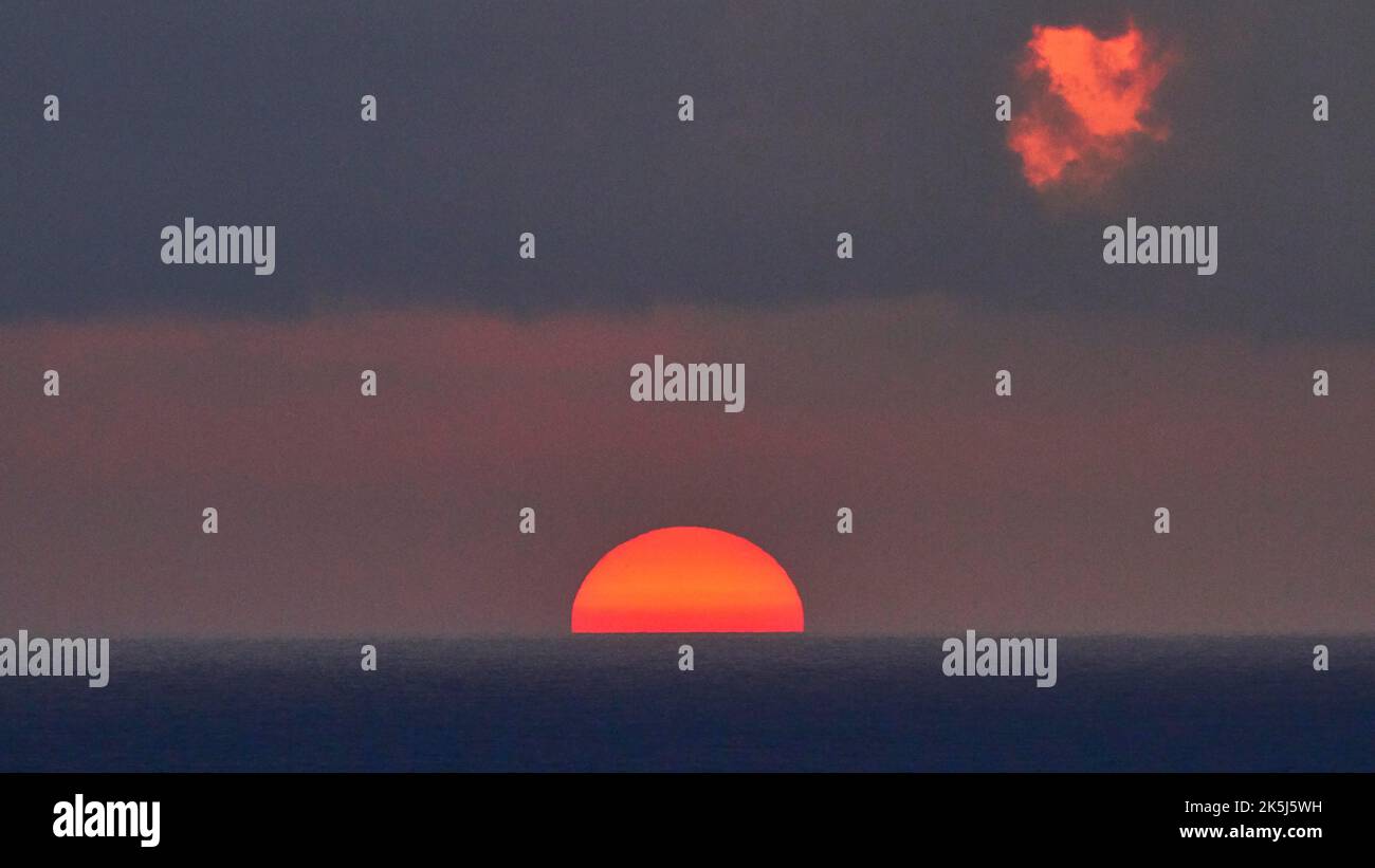 Sun as a fiery red large ball, blue-purple sky, single cloud ...