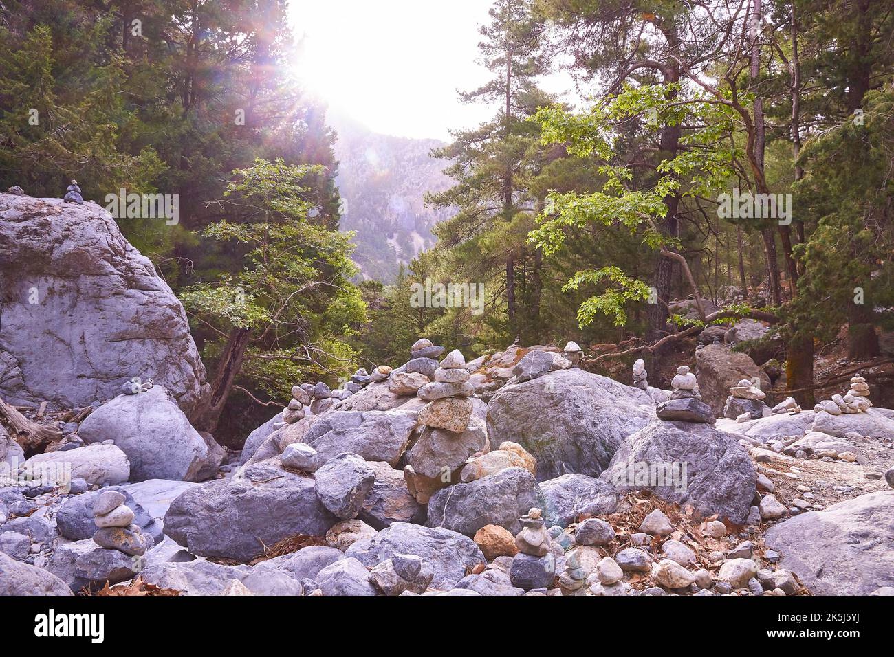 Cairns, rocks in streambed, trees, outshining sun, backlight, Samaria ...