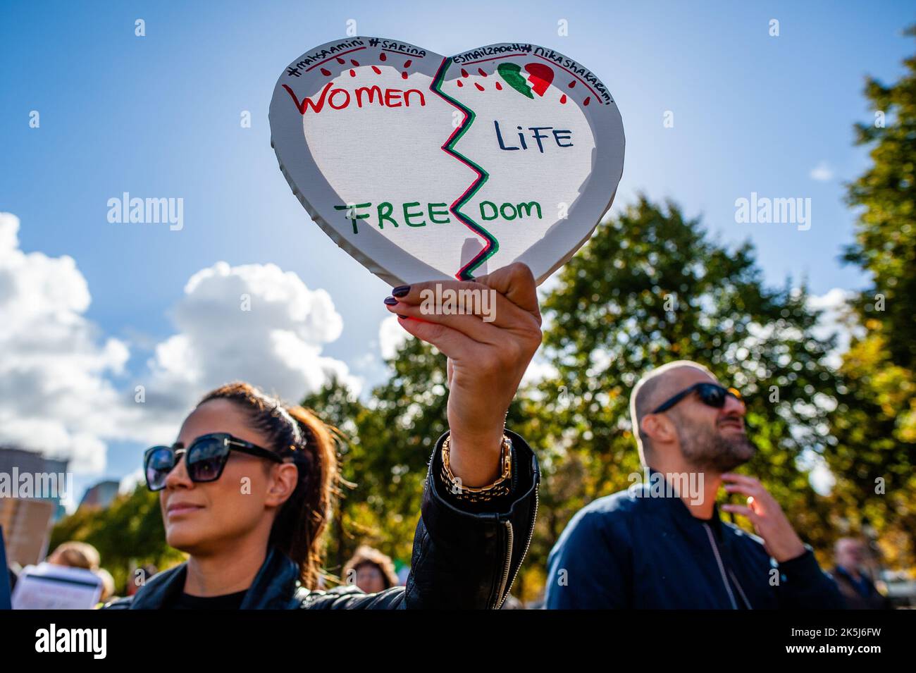 A woman is seen holding a placard in a shape of a heart saying Women ...
