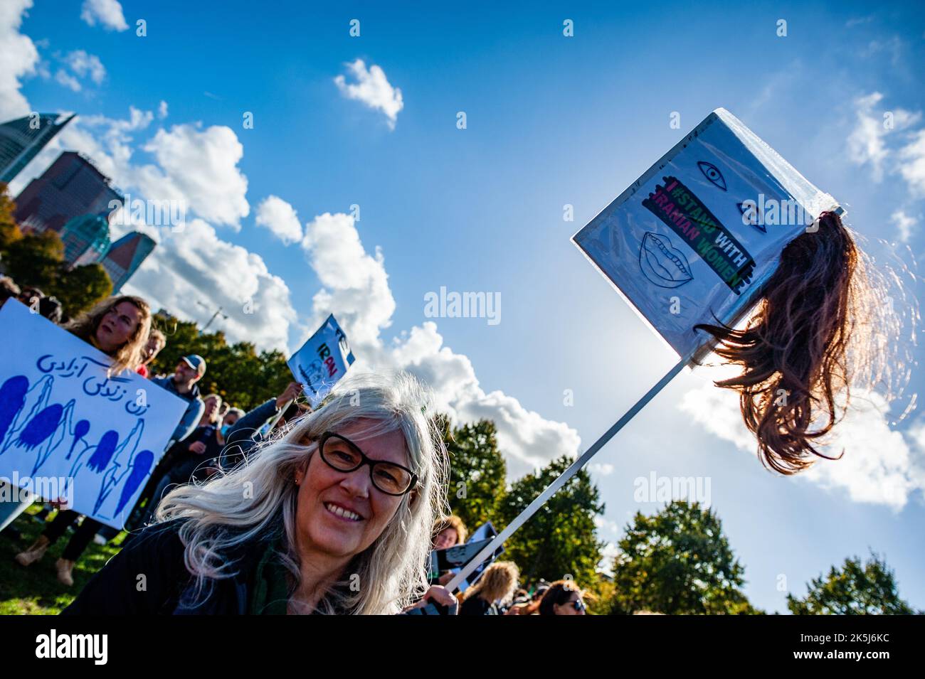 A woman is seen holding a placard with a wig to show her support with ...