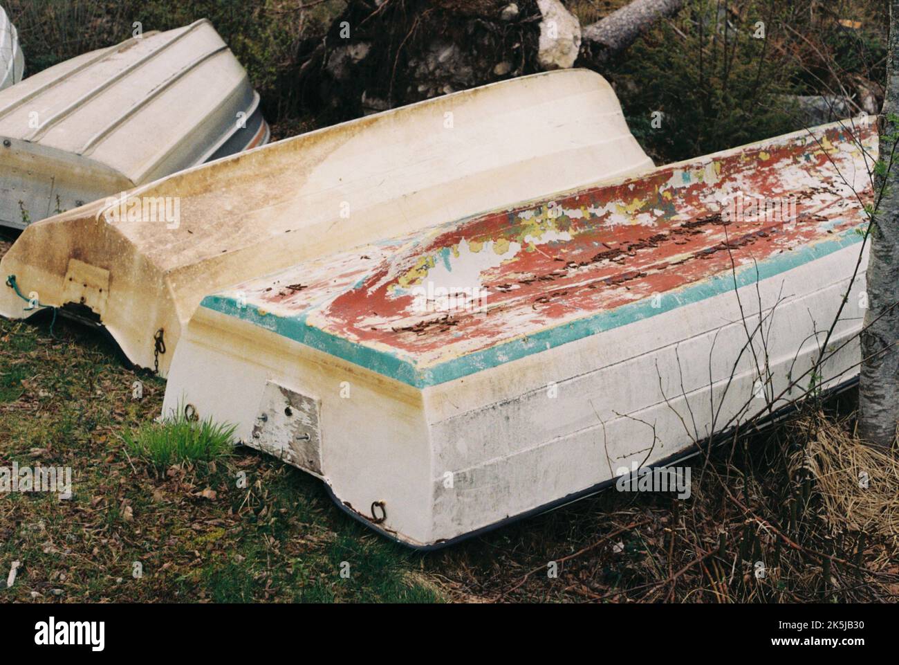 A closeup of old dirty white abandoned boats flipped over in the middle ...