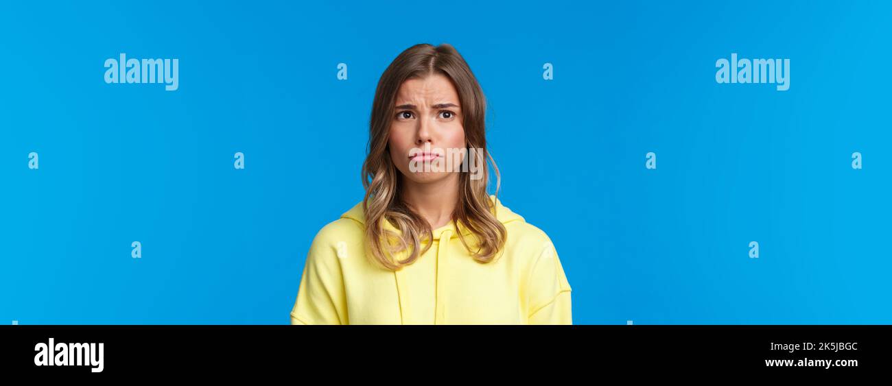 Close-up portrait gloomy sad cute jealous blond girl in yellow hoodie ...