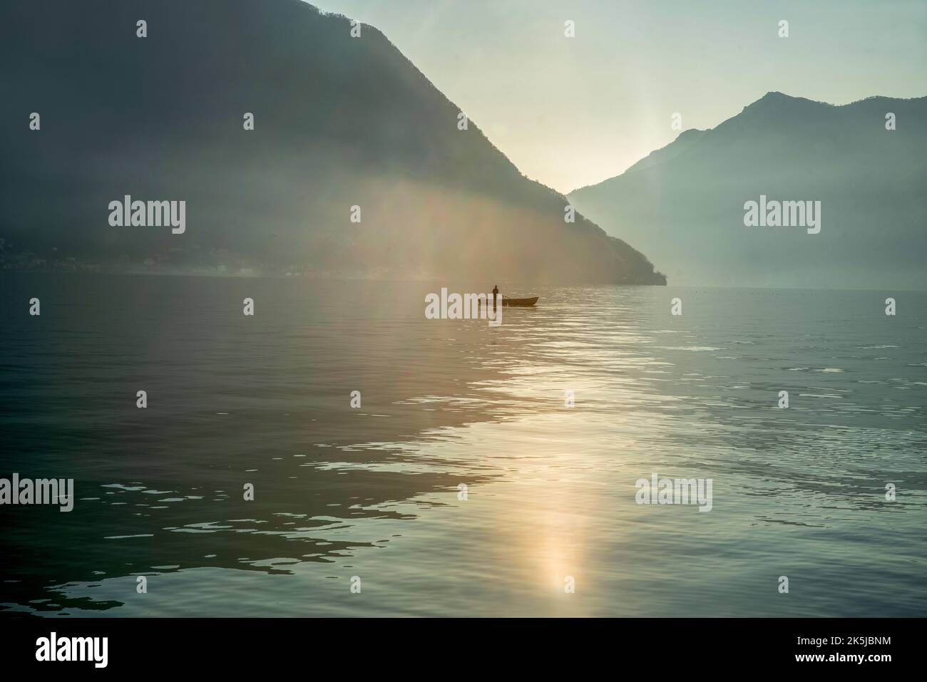 Idyllic landscape on lake Como (a little fog) with boat of fishier and ...