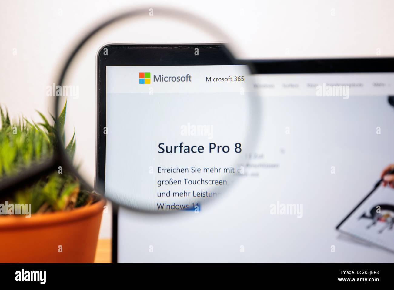 The logo of Microsoft on a laptop desktop under a magnifying glass ...