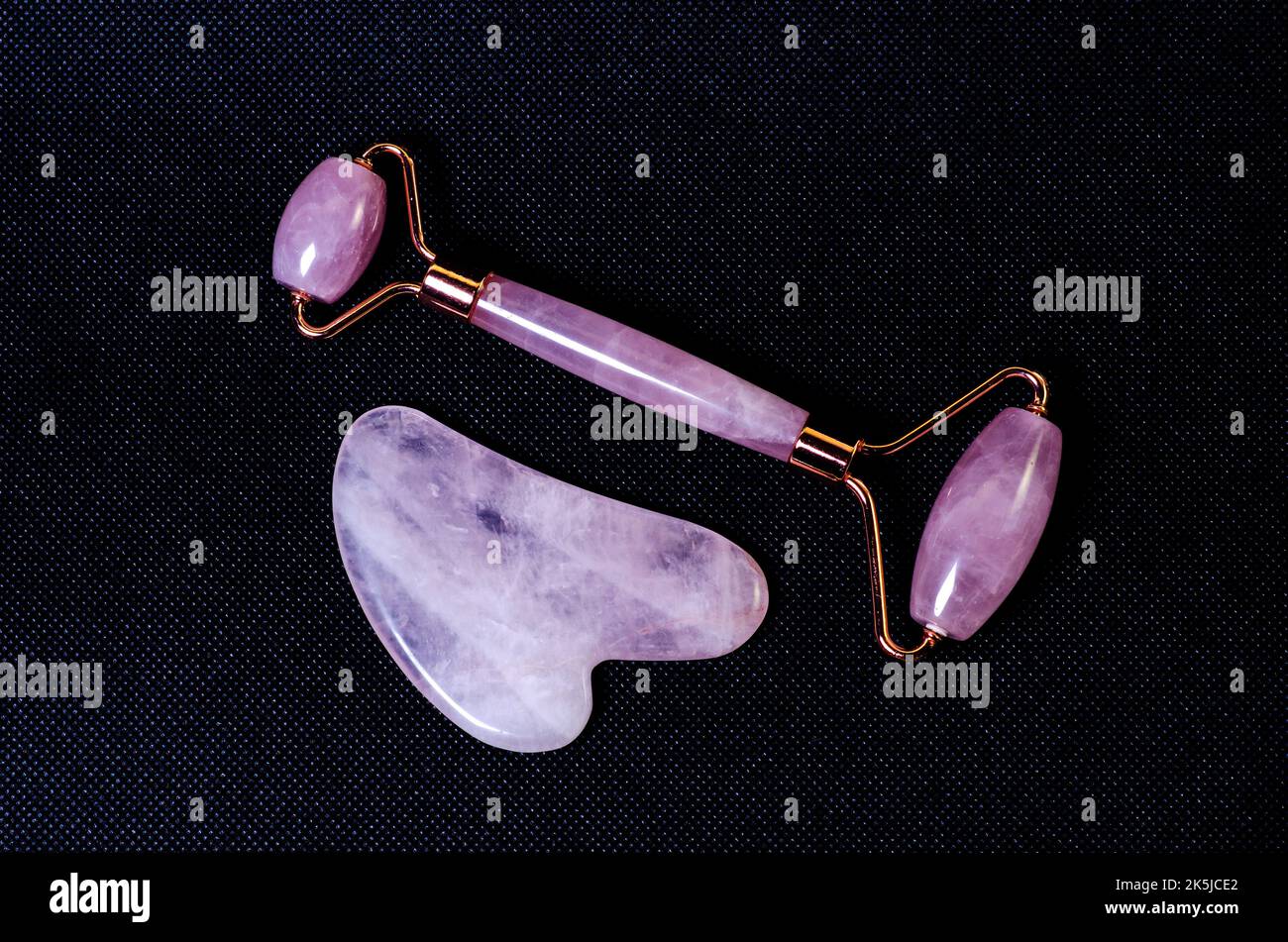 rose quartz facial roller and massage stone gua sha isolated on white ...