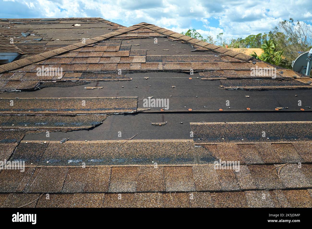 Damaged house roof with missing shingles after hurricane Ian in Florida ...