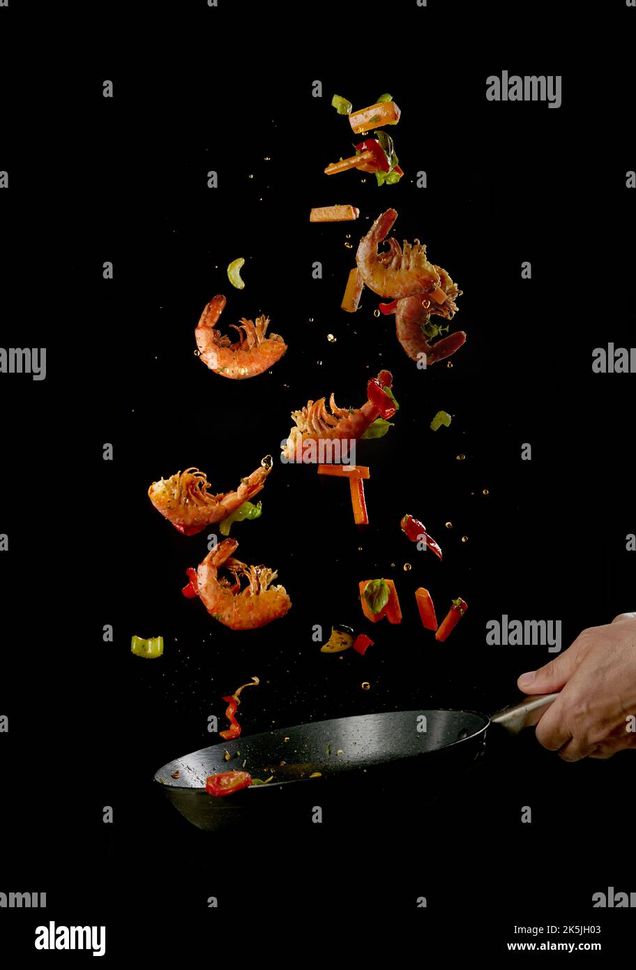 Crop anonymous male chef tossing food in frying pan while preparing ...
