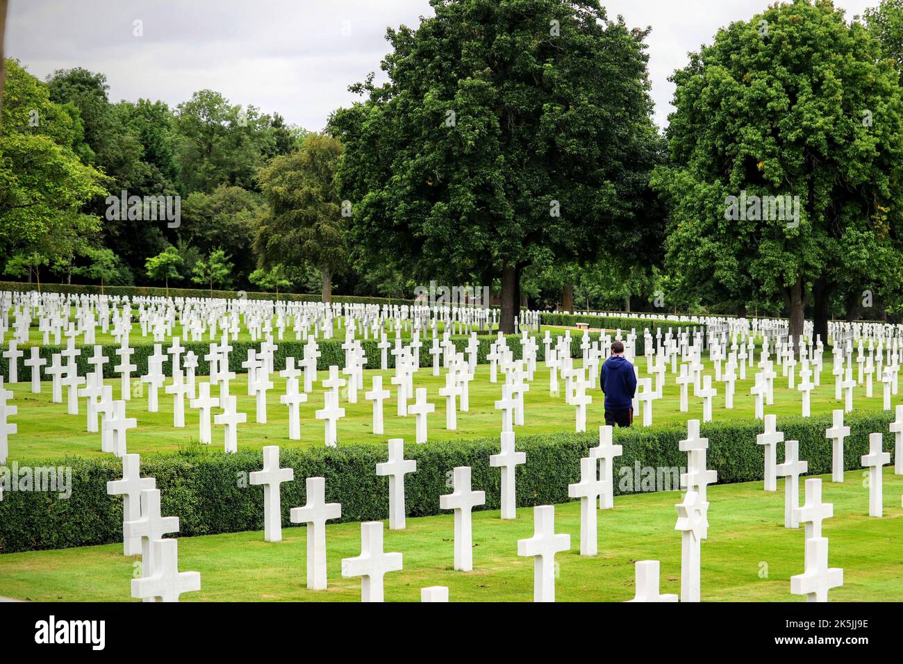 A man mourning a lost loved one in a graveyard with white crosses ...