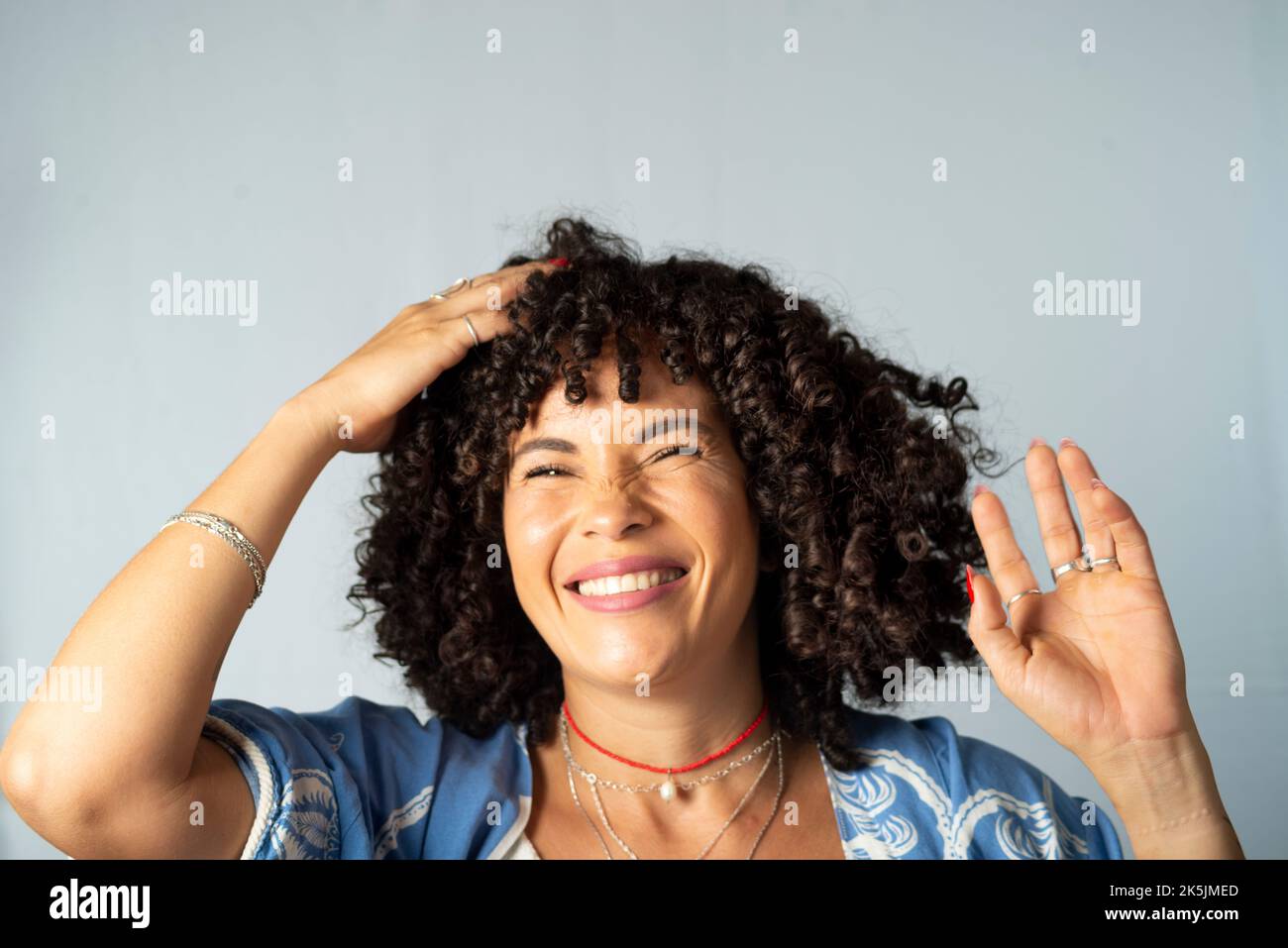 Portrait Of Smiling Beautiful Curly Hair Model Against Light Background