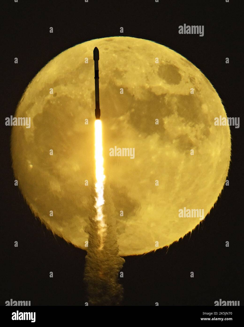 A SpaceX Falcon 9 rocket transits a near full moon as it launches from ...