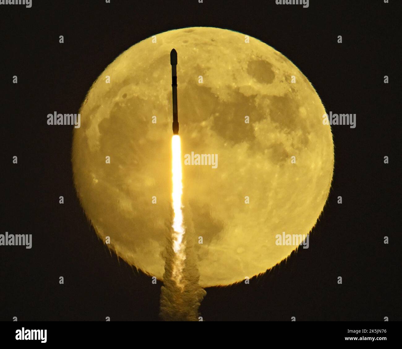 A SpaceX Falcon 9 rocket transits a near full moon as it launches from ...