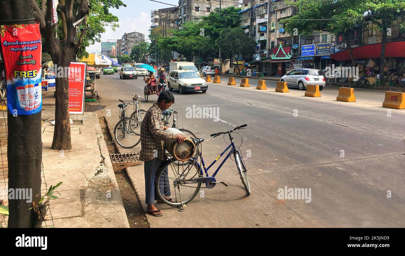 Yangon, Myanmar - 10 March 2018: Burmese man loading an old gas cylinder on the back of his ...