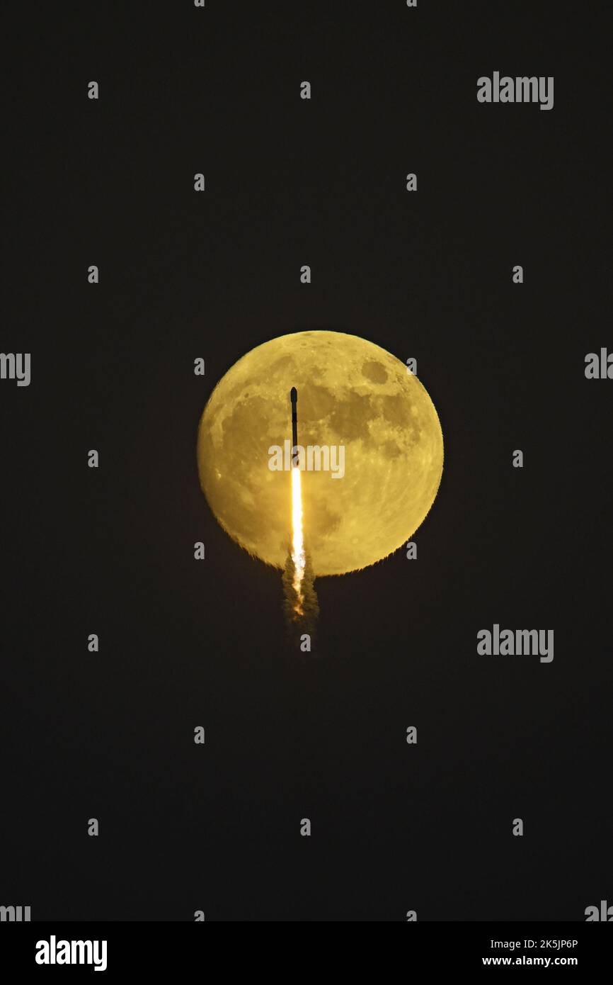 A SpaceX Falcon 9 rocket transits a near full moon as it launches from ...