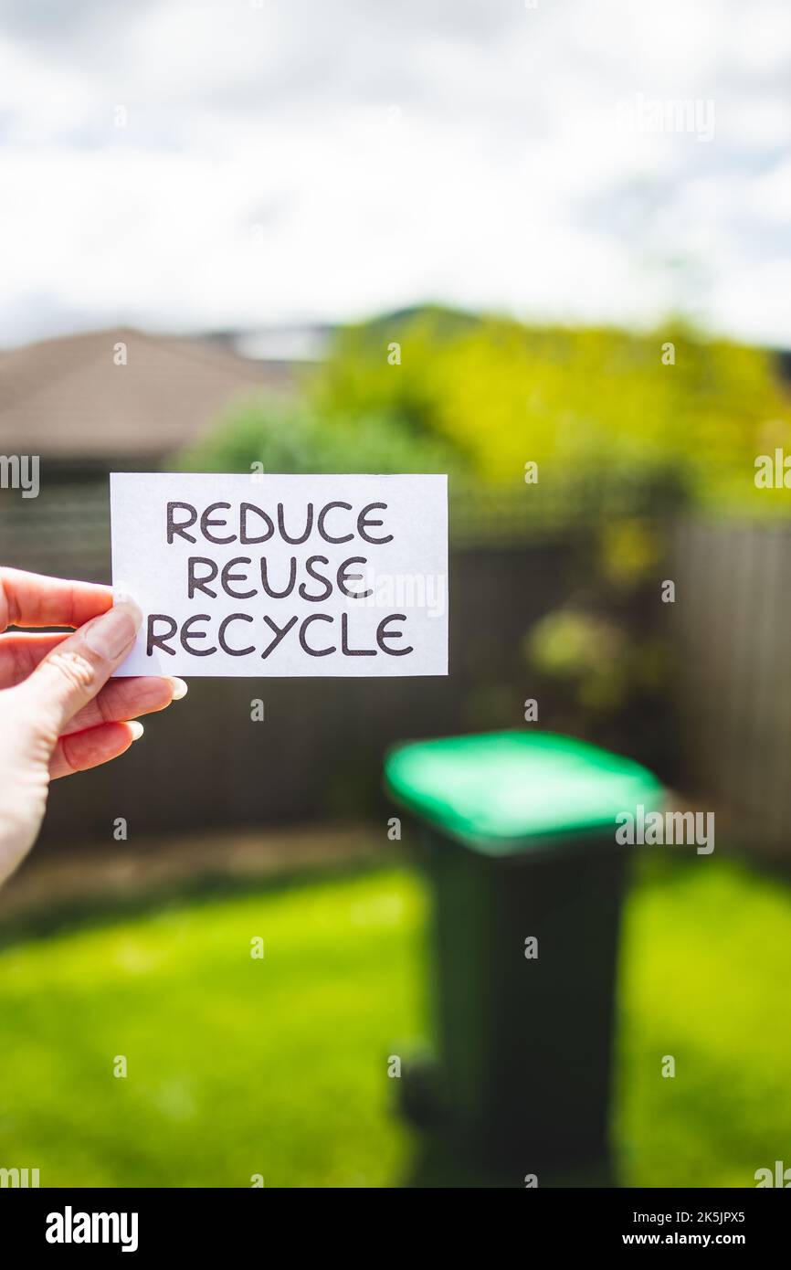 reduce reuse recycle sign in front of backyard bokeh with garbage bin ...