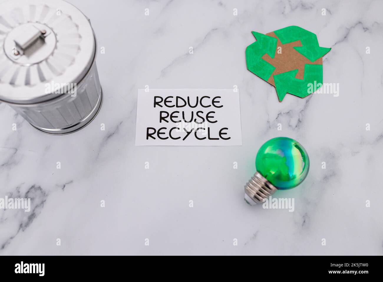 reduce reuse recycle sign with mini trash can next to green light bulb ...
