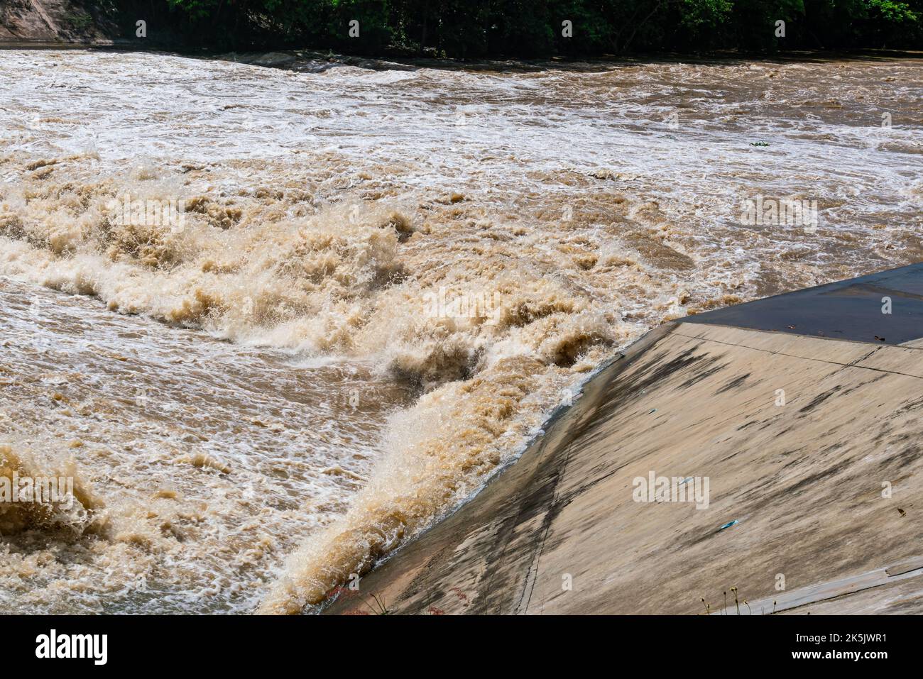 Muddy water streams rushing rapidly on a river after rain storm. The ...