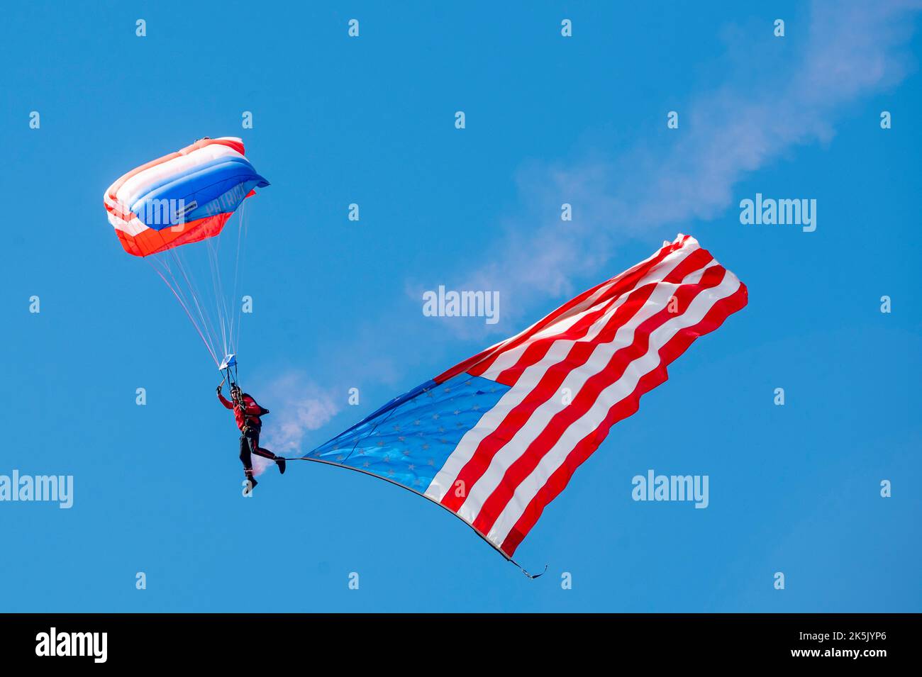 A member of the Patriots Parachute team with an American Flag strapped ...