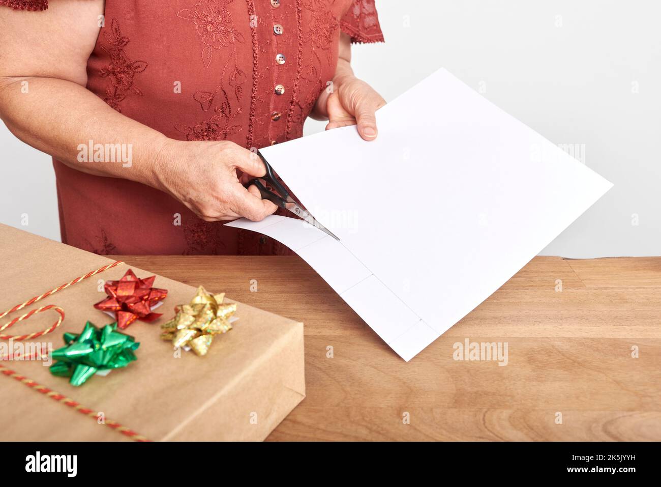 Unrecognizable mature woman cutting with scissors a piece of white ...