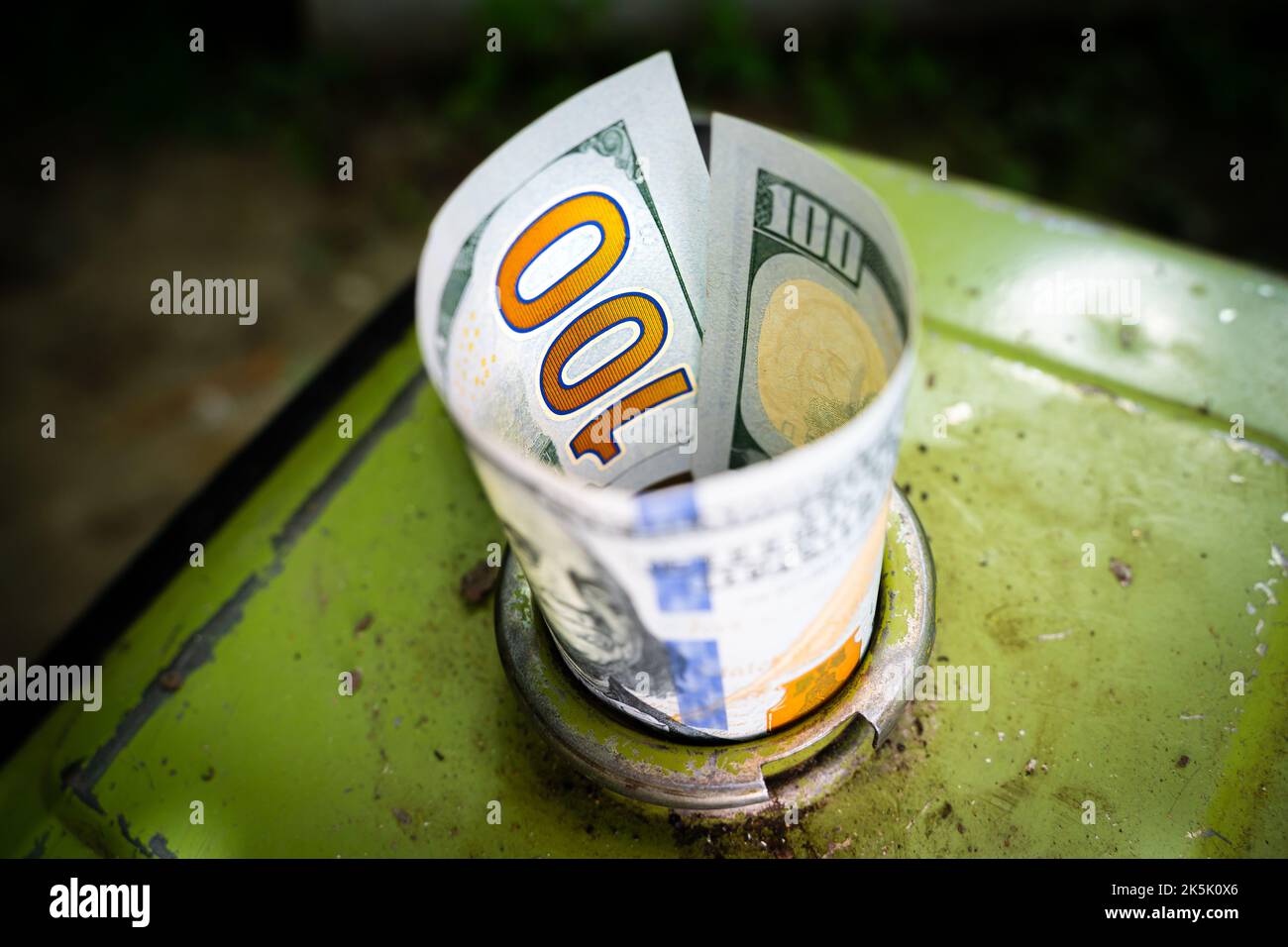 A hundred dollar bill is twisted into a tube sticking out of the gas ...