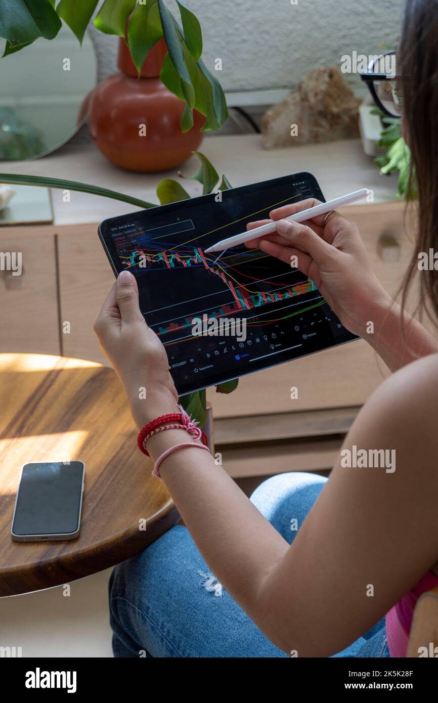 young woman, watching the stock market on her tablet, while drawing on the chart Stock Photo - Alamy