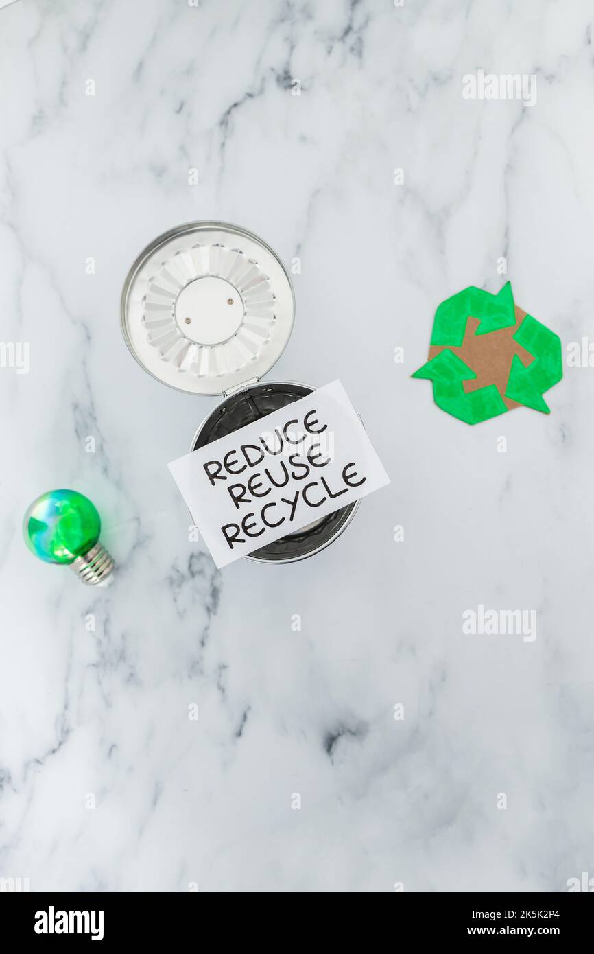 reduce reuse recycle sign with mini trash can next to green light bulb ...