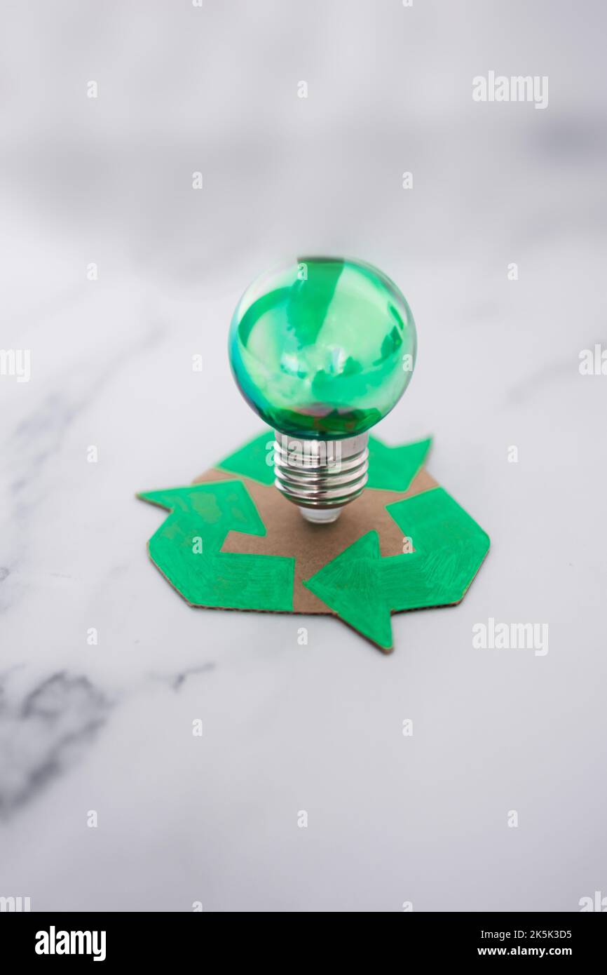 recycle sign with green light bulb standing on it, concept of ...