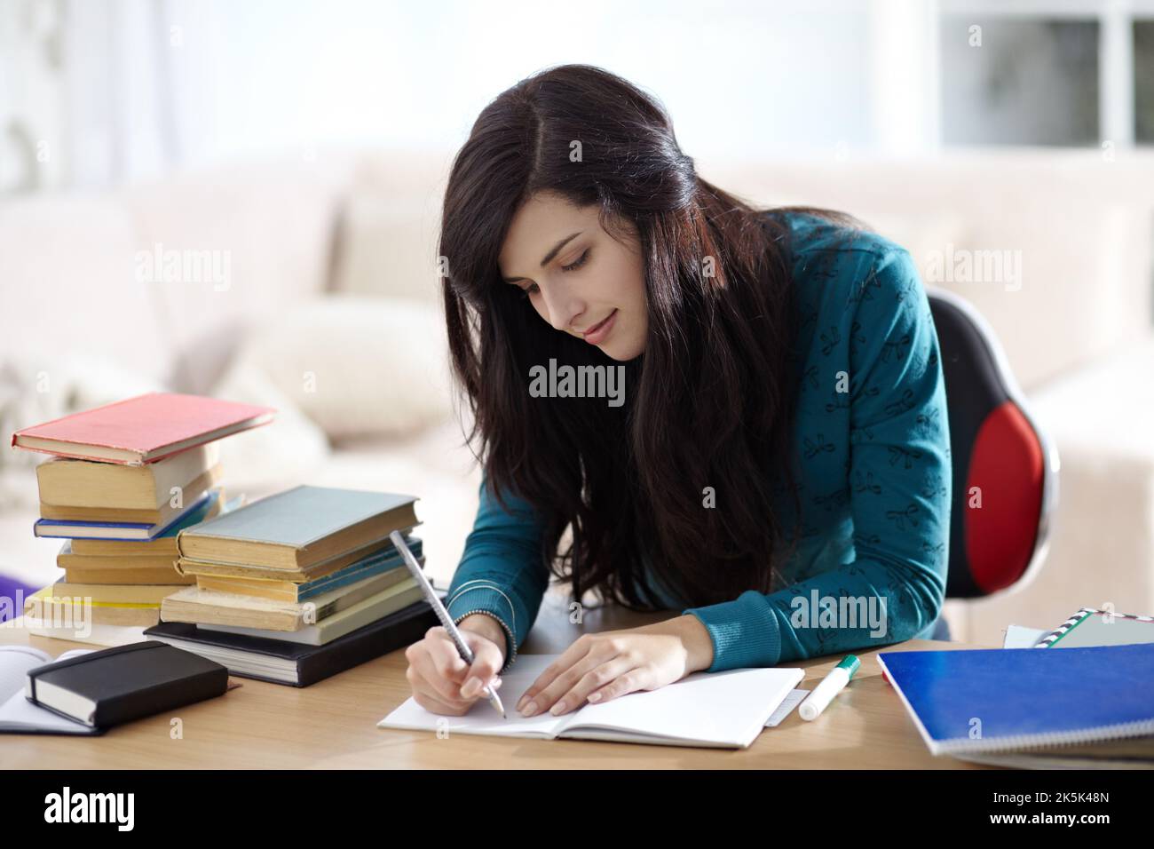 Shes a focused student. Attractive young student sitting at a desk and ...