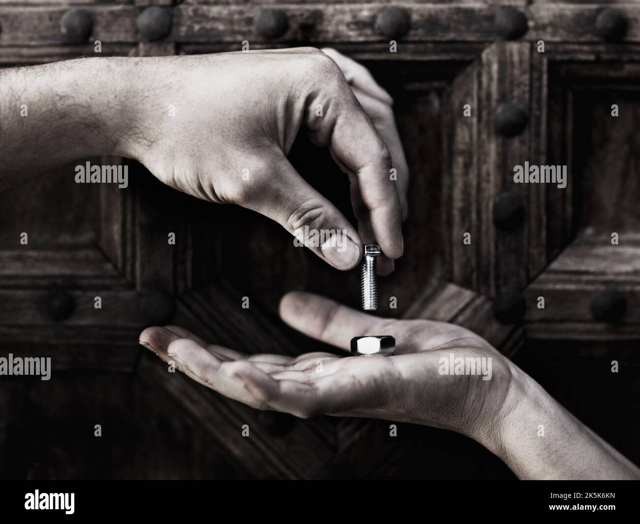 The perfect fit. Closeup of two hands screwing a nut and bolt together ...