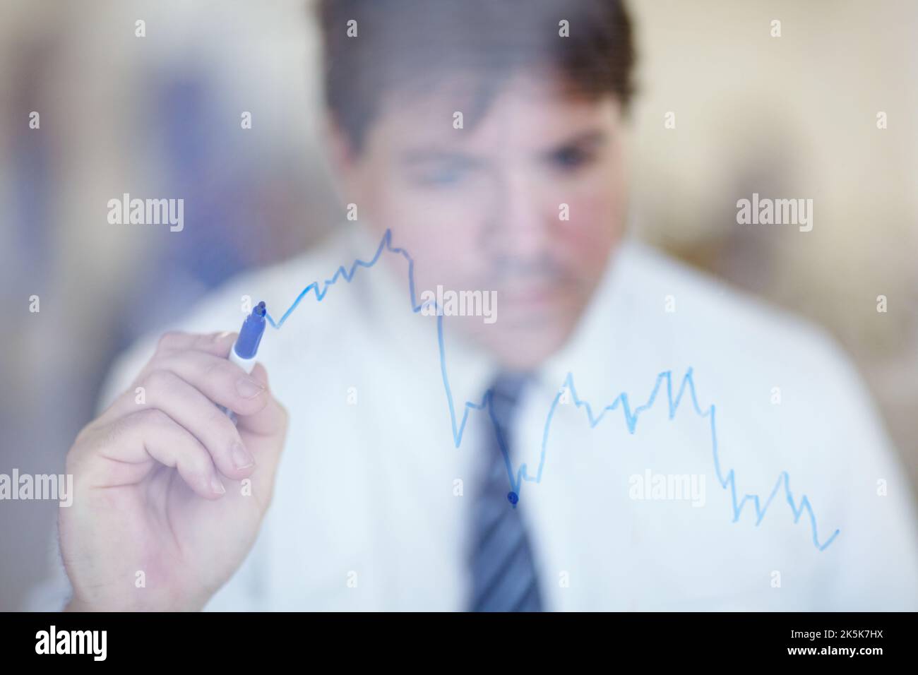 Charting his growth. a businessman writing on a clear wall with a blue ...