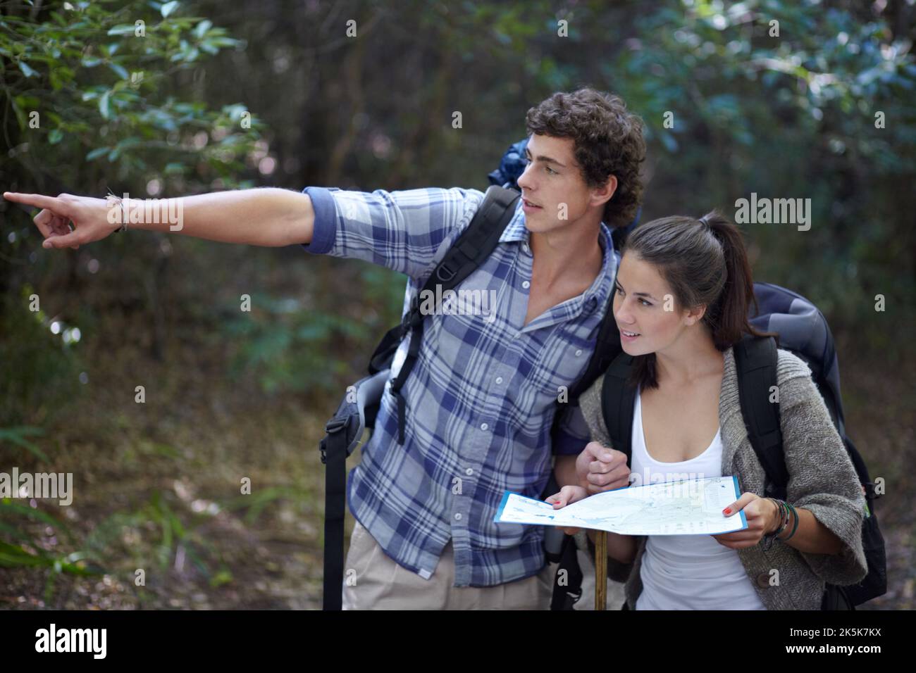 Lets go that way. A young man pointing out the path while his ...