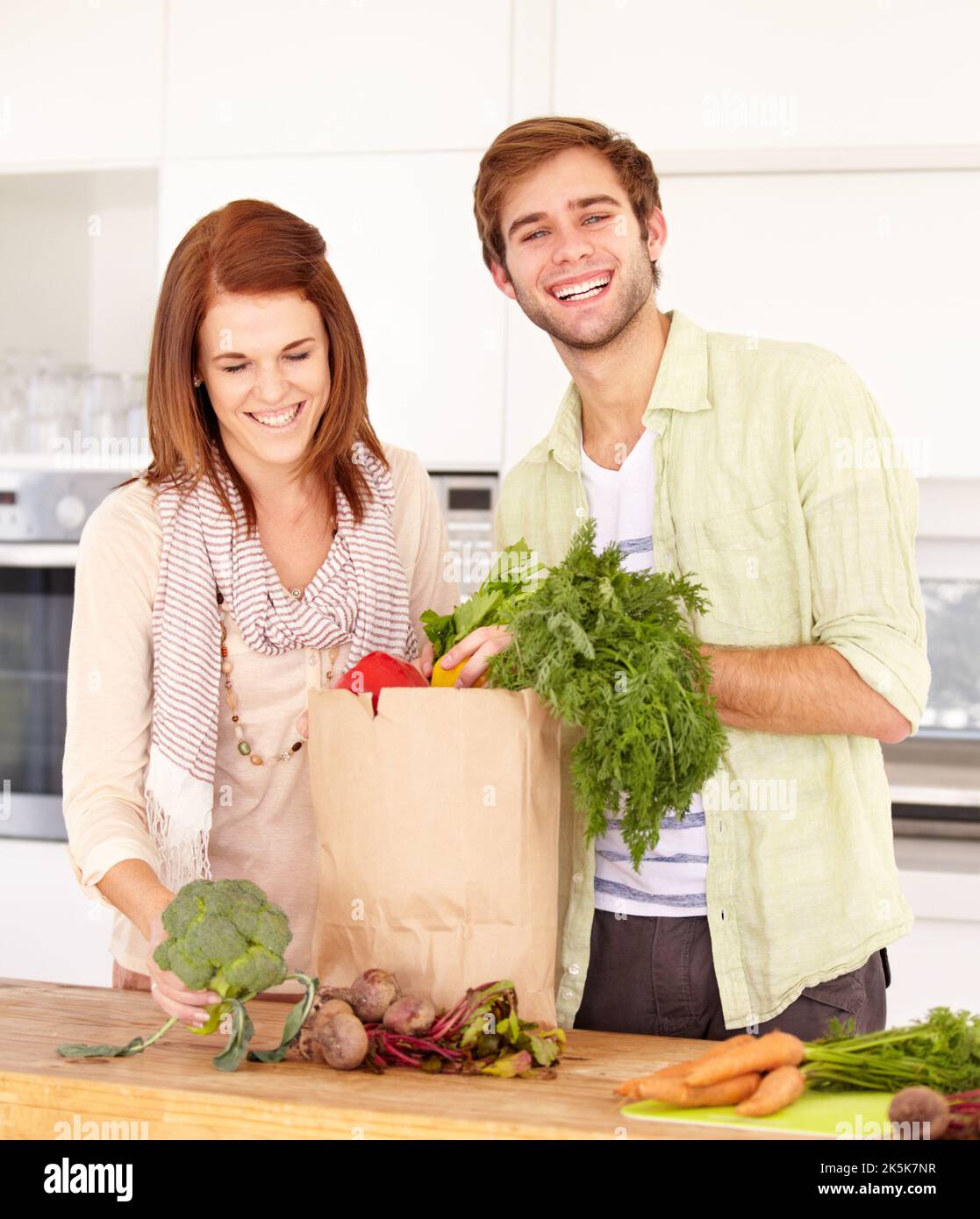 Unpacking the groceries. A happy couple unpacking their grocery bag in ...