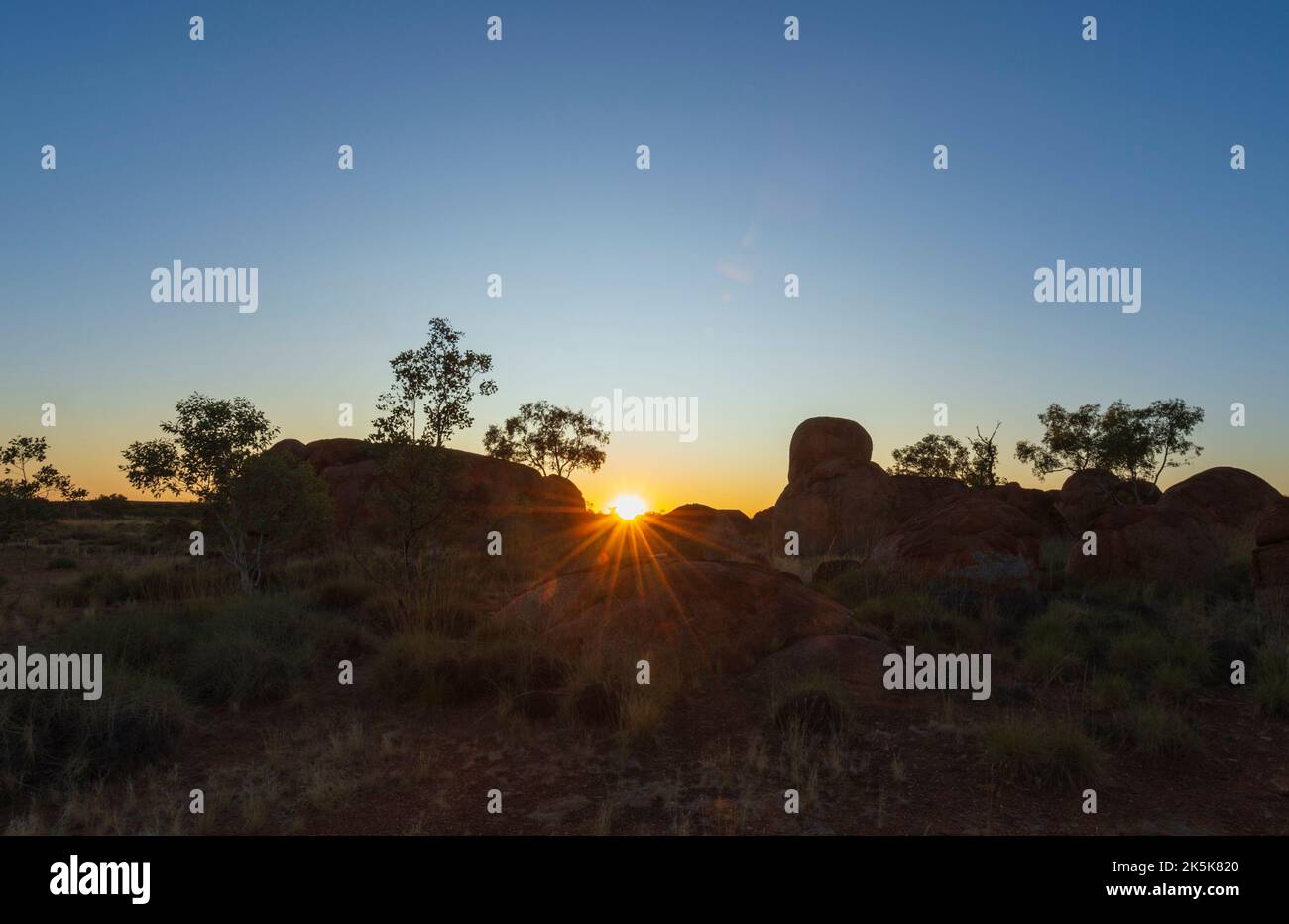 Sun on the horizon at sunrise, Devil's Marbles, a popular tourist ...