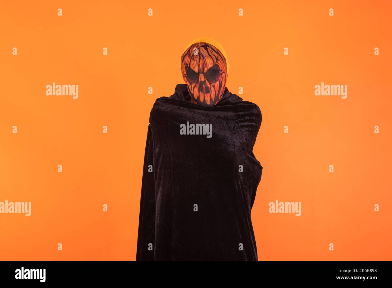 Person with wearing Jack o Lantern pumpkin mask and black hooded cape ...