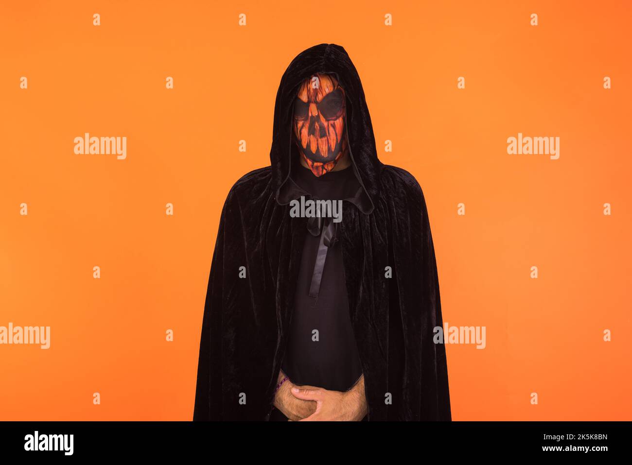 Person with wearing Jack o Lantern pumpkin mask and black hooded cape ...