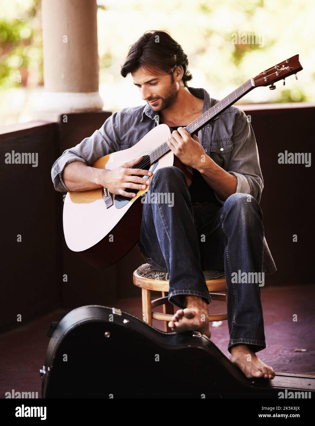 Expressing himself through his music. Relaxed young man sitting and ...