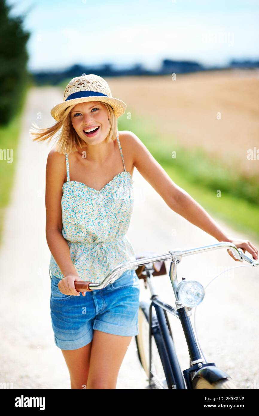 Taking a walk along a country lane. Happy young woman walking alongside ...