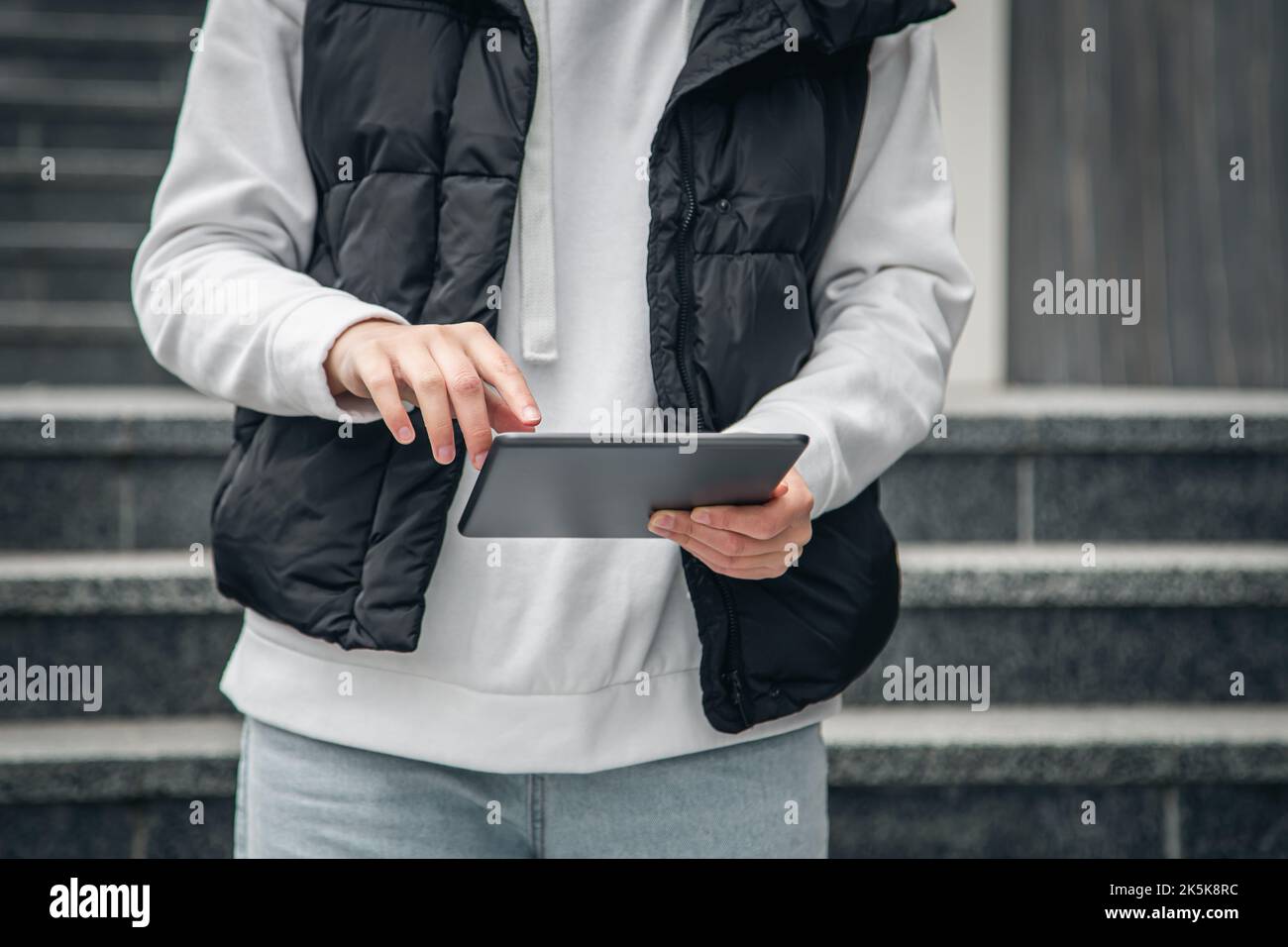Close-up, a woman is using a tablet outside Stock Photo - Alamy