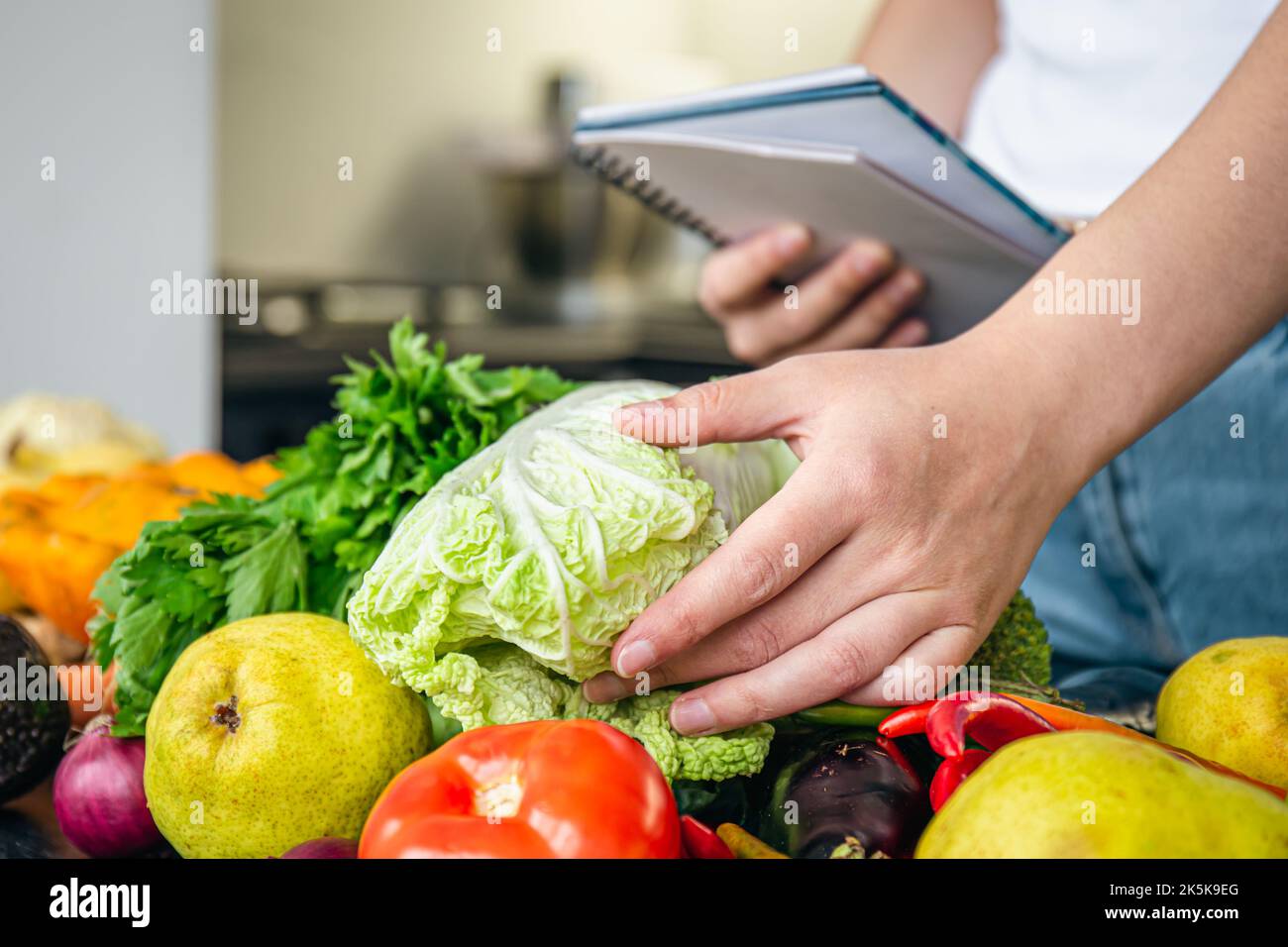 Woman with notepad and vegetables on the kitchen table preparing a ...