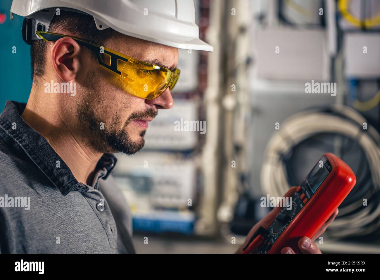 Man, an electrical technician working in a switchboard with fuses, uses a tablet Stock Photo - Alamy