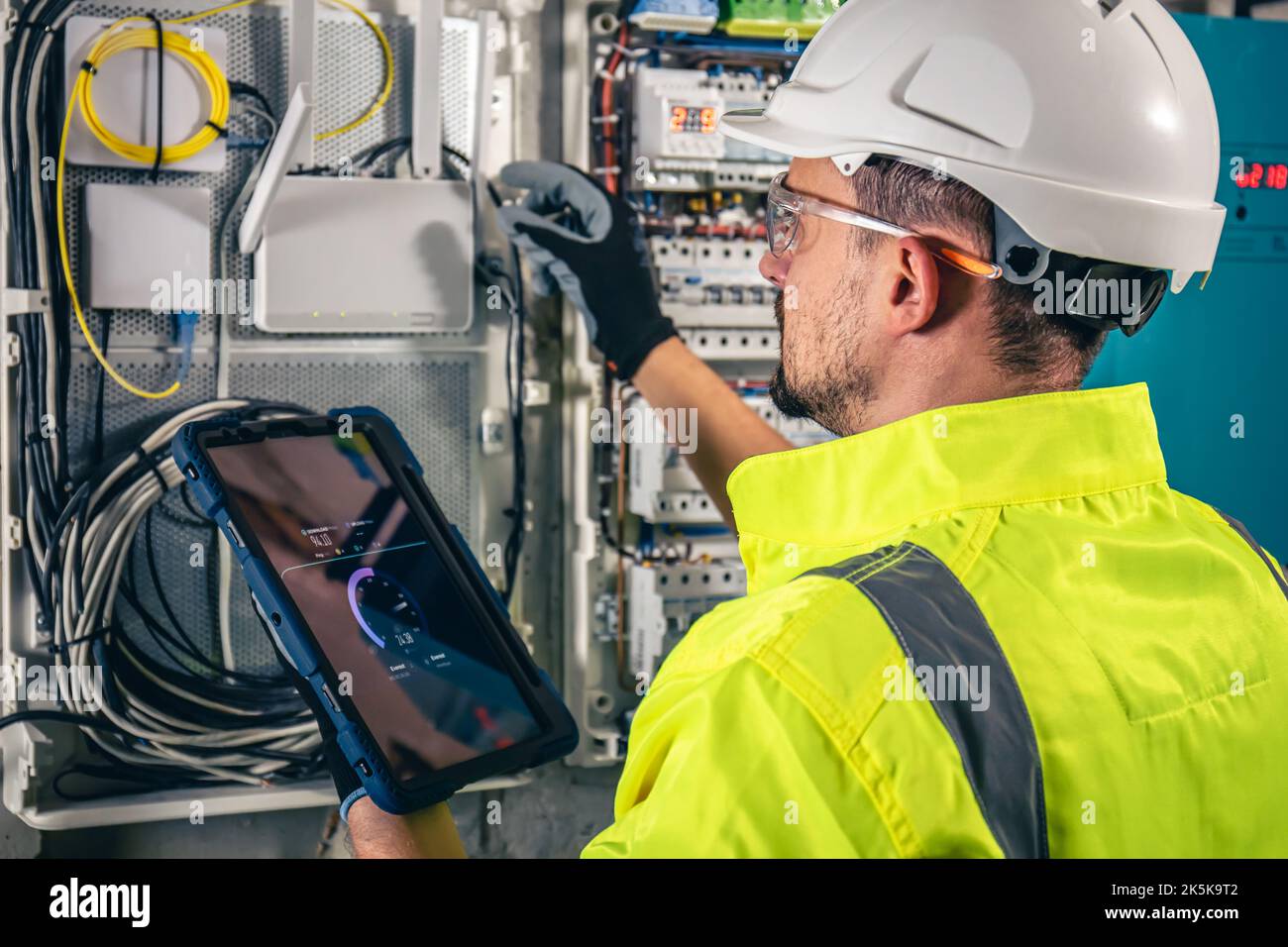Man, an electrical technician working in a switchboard with fuses, uses ...