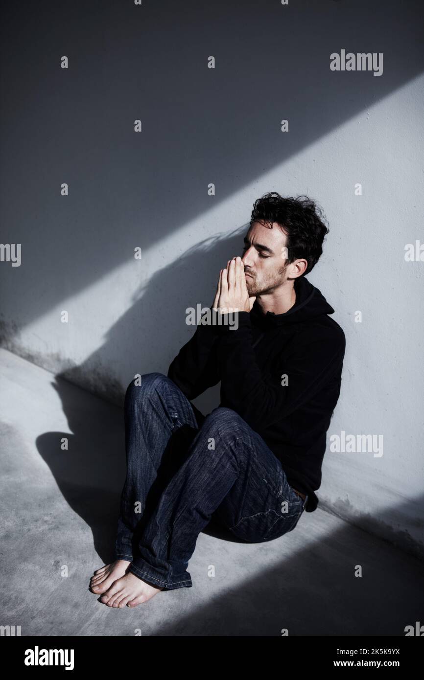 Sometimes prayer is your only hope. A young man sitting barefoot on the ...