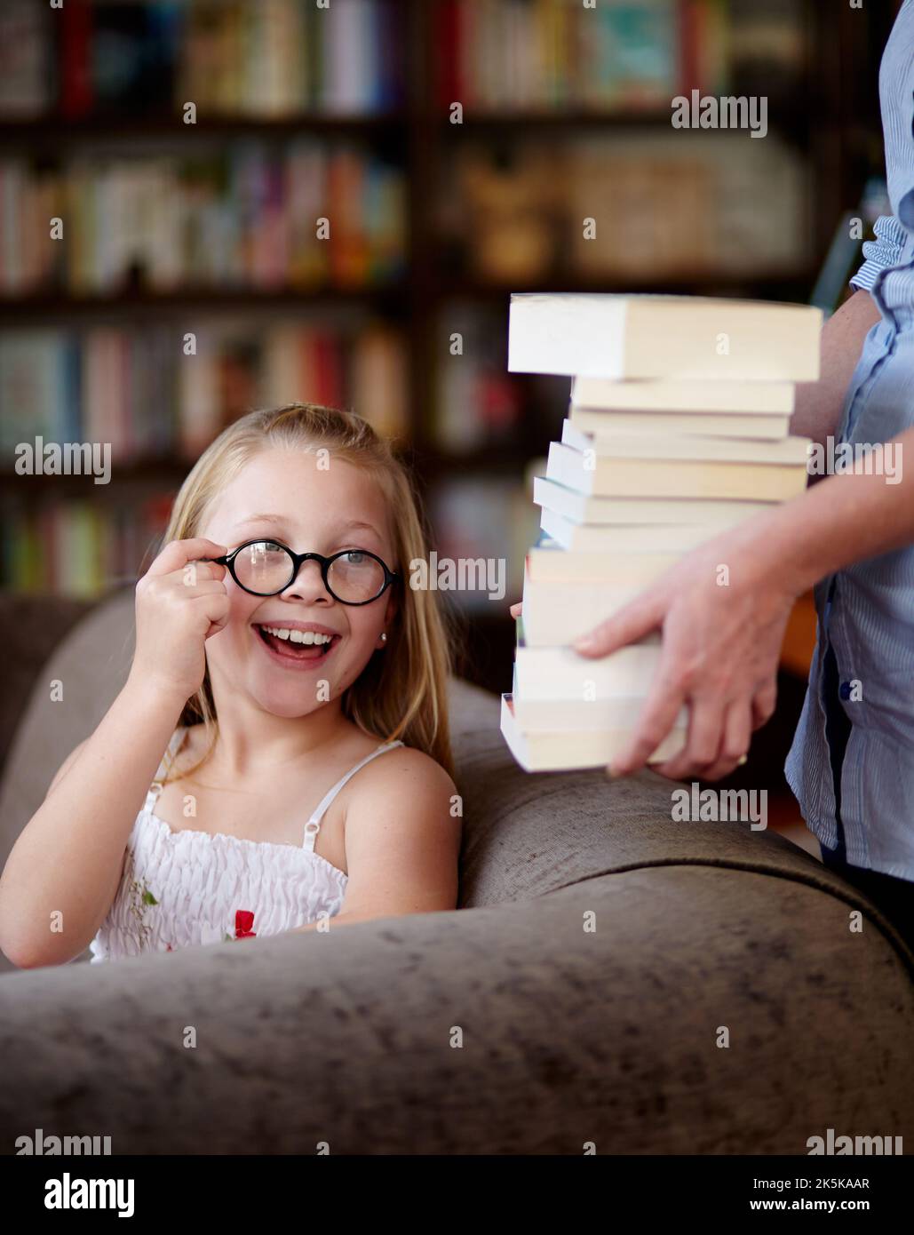 Shes A Little Bookworm A Cute Little Blonde Girl Smiling As Someone Brings Her A Stack Of Books