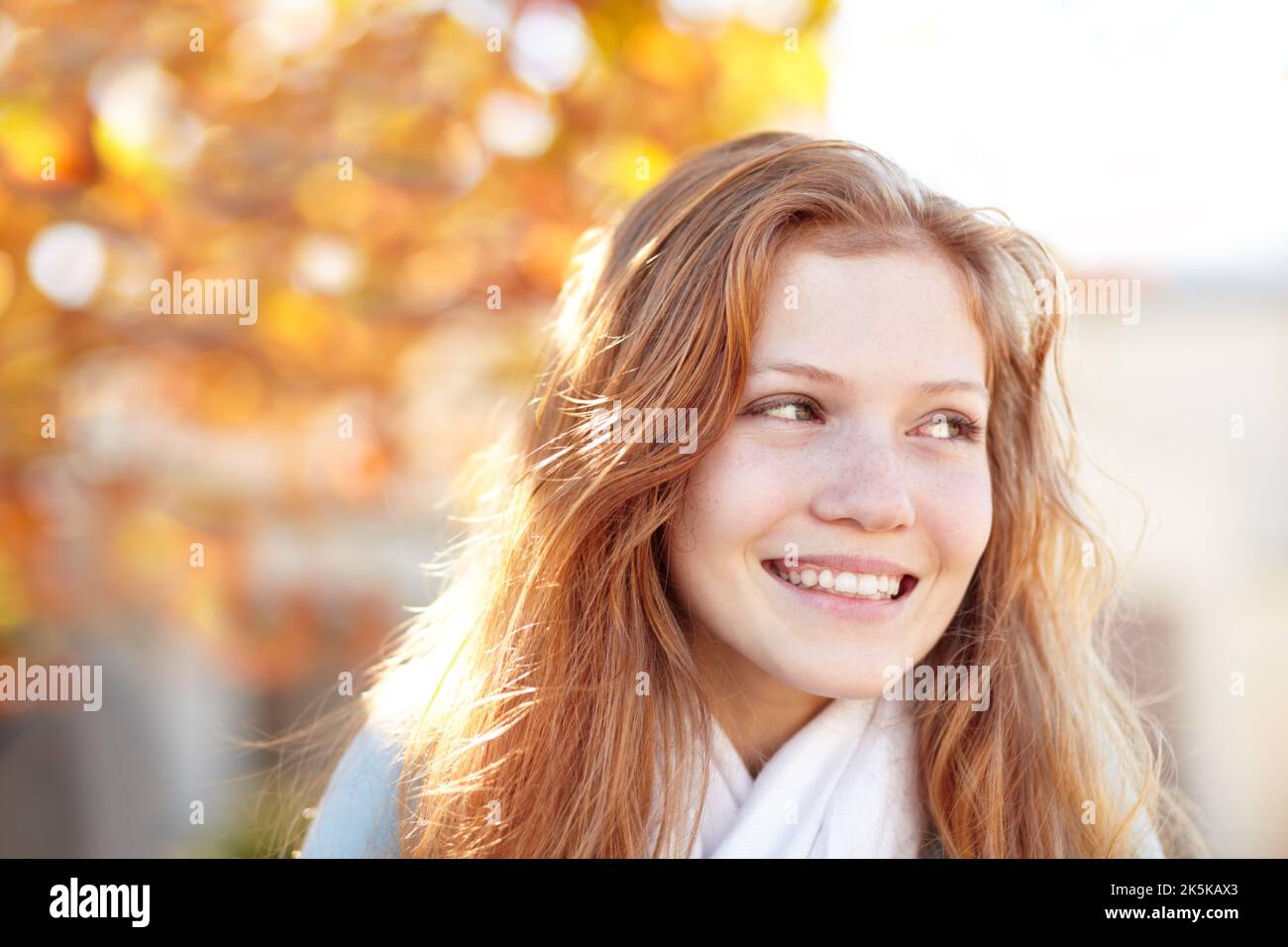 Enjoying the warm glow of autumn. A pretty young girl standing outside ...