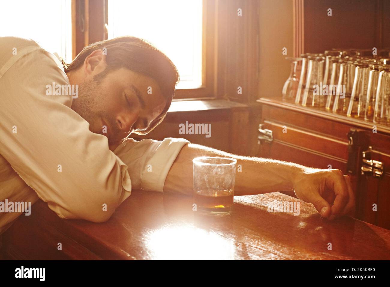 Late nights. A handsome young man sleeping on the counter at a bar ...