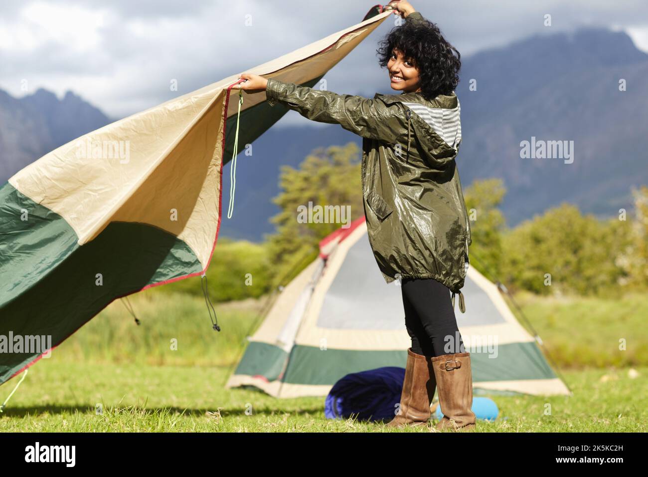 Putting up a tent is easy. Attractive young woman setting up a tent ...